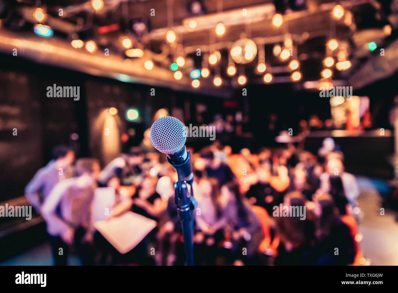 Microphone stand in an event hall, audience in the blurry background ...