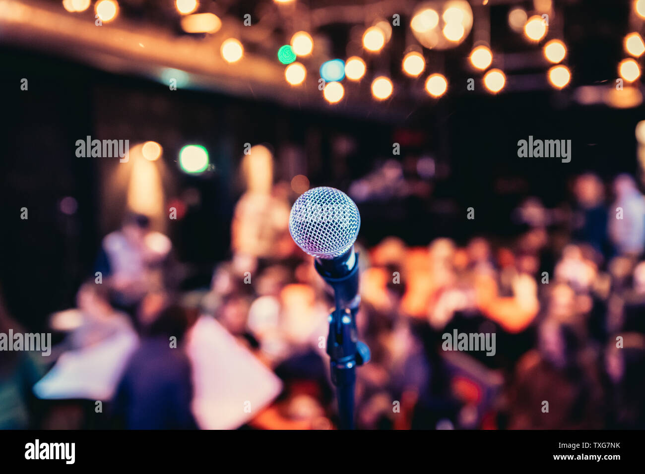 Microphone stand in an event hall, audience in the blurry background ...