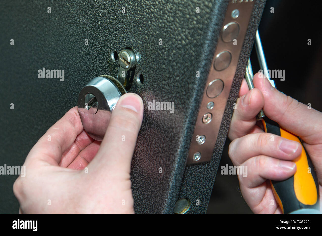 Man fixing the door with screwdriver. Door lock repair Stock Photo - Alamy