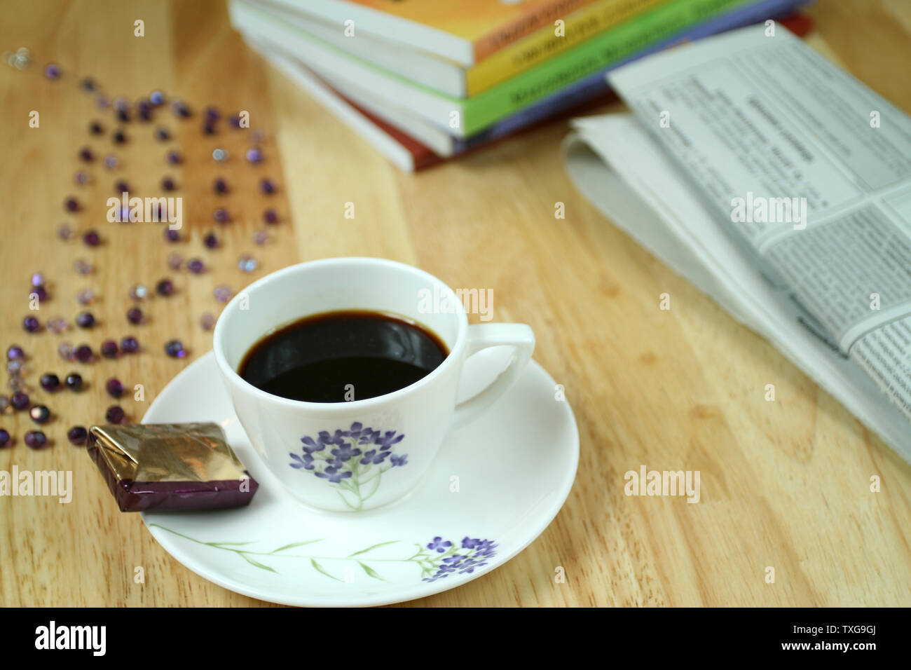 A cup of morning coffee surrounded with newspaper and colorful books ...