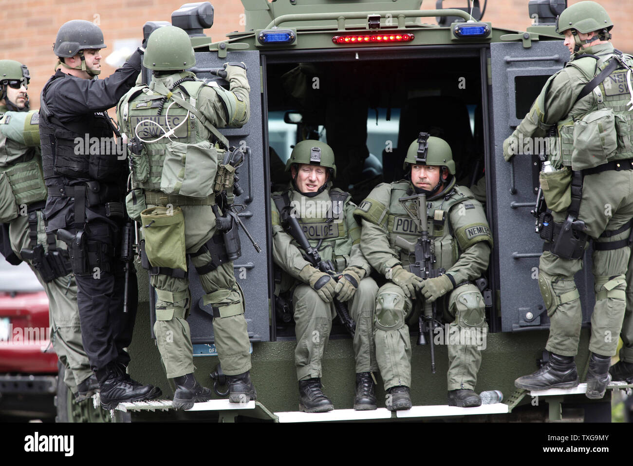 SWAT team members are driven down School Street in Watertown ...