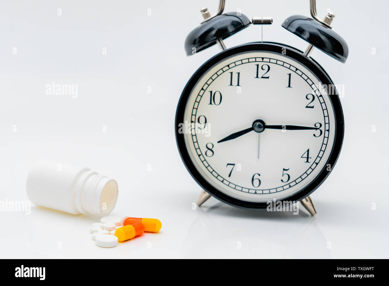 Tablets, capsules and alarm clocks on white background Stock Photo - Alamy