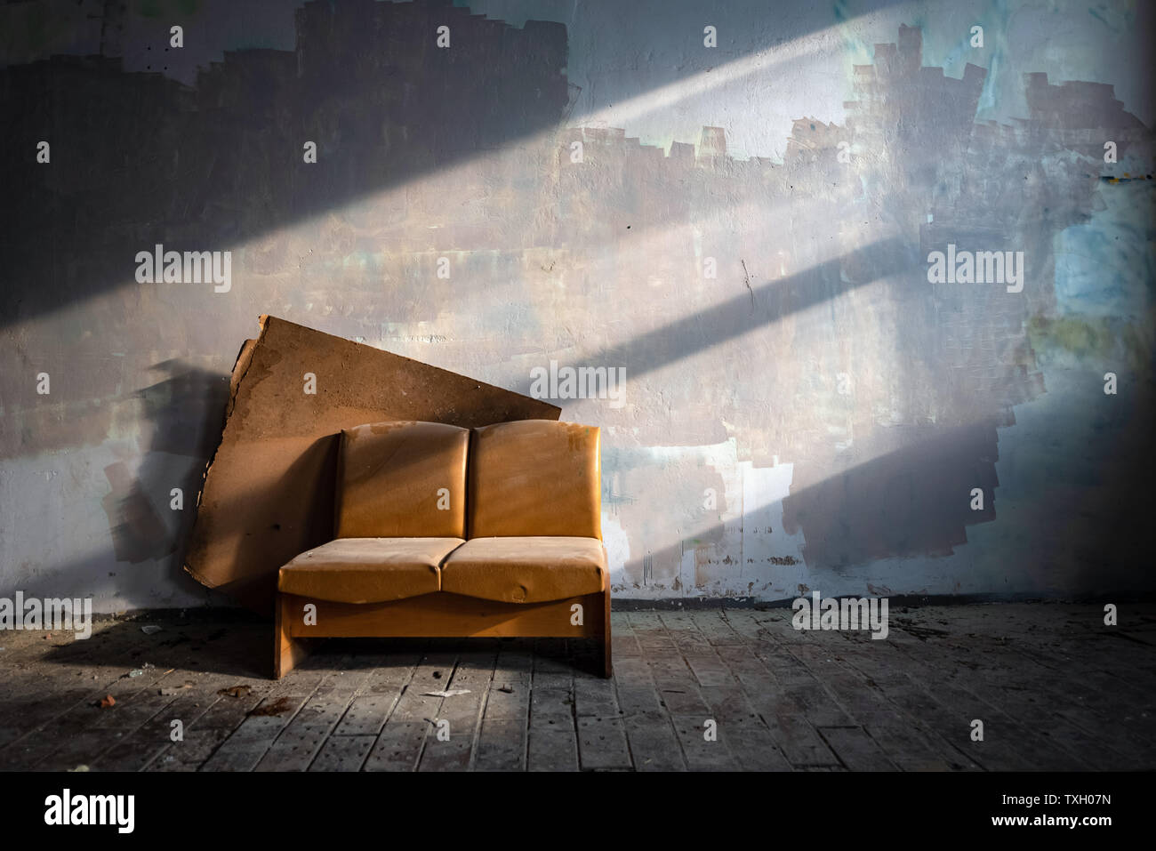 Old leather couch in abandoned factory building side lit by sun. Rustic ...
