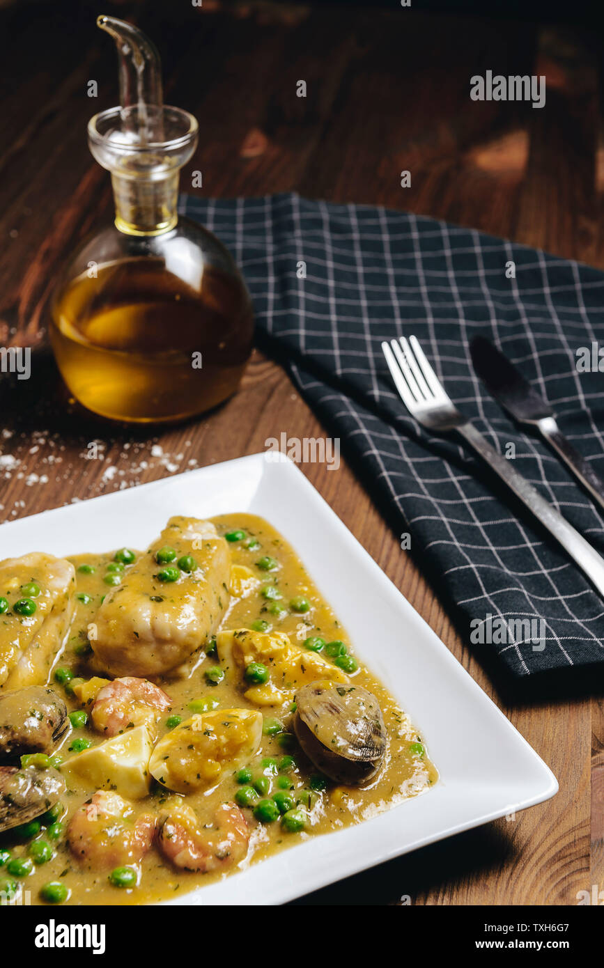 vertical photo of a healthy traditional spanish hake dish in green ...