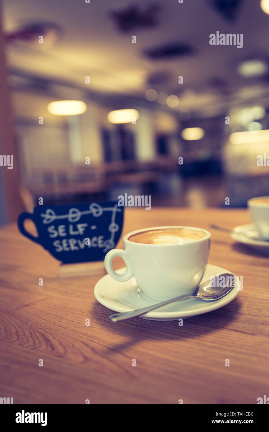 Cup of cappuccino, plate with self-service text on it Stock Photo - Alamy
