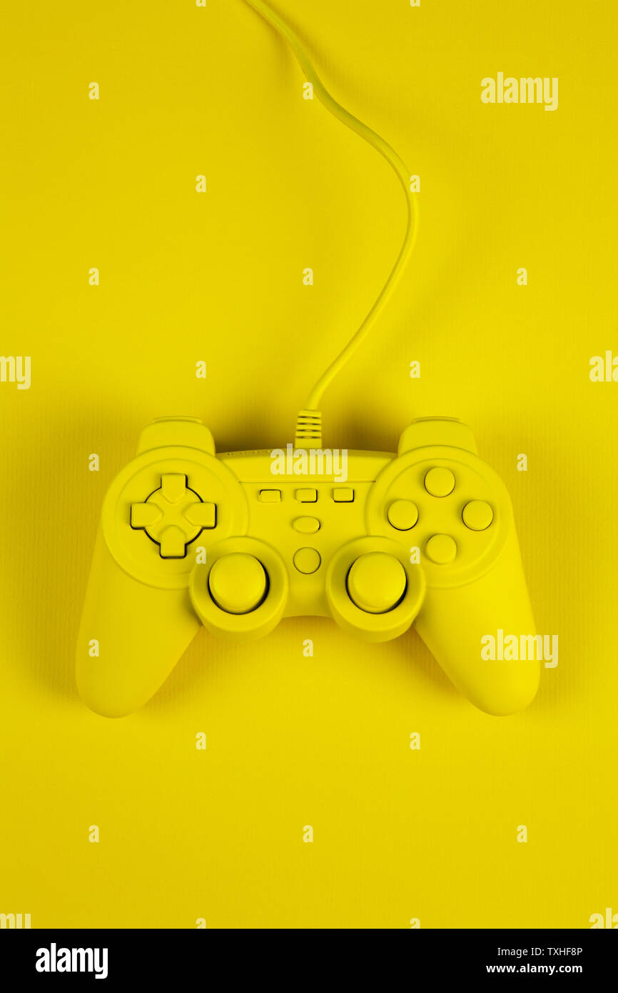 a yellow painted video game controller on a plain background of the ...