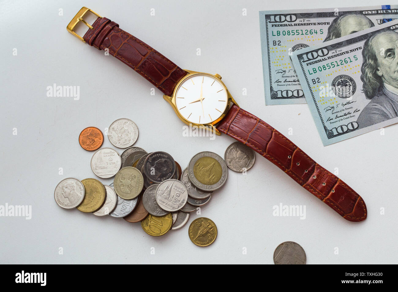 Time is money. Wrist watch with dollar bills and coins on a white ...