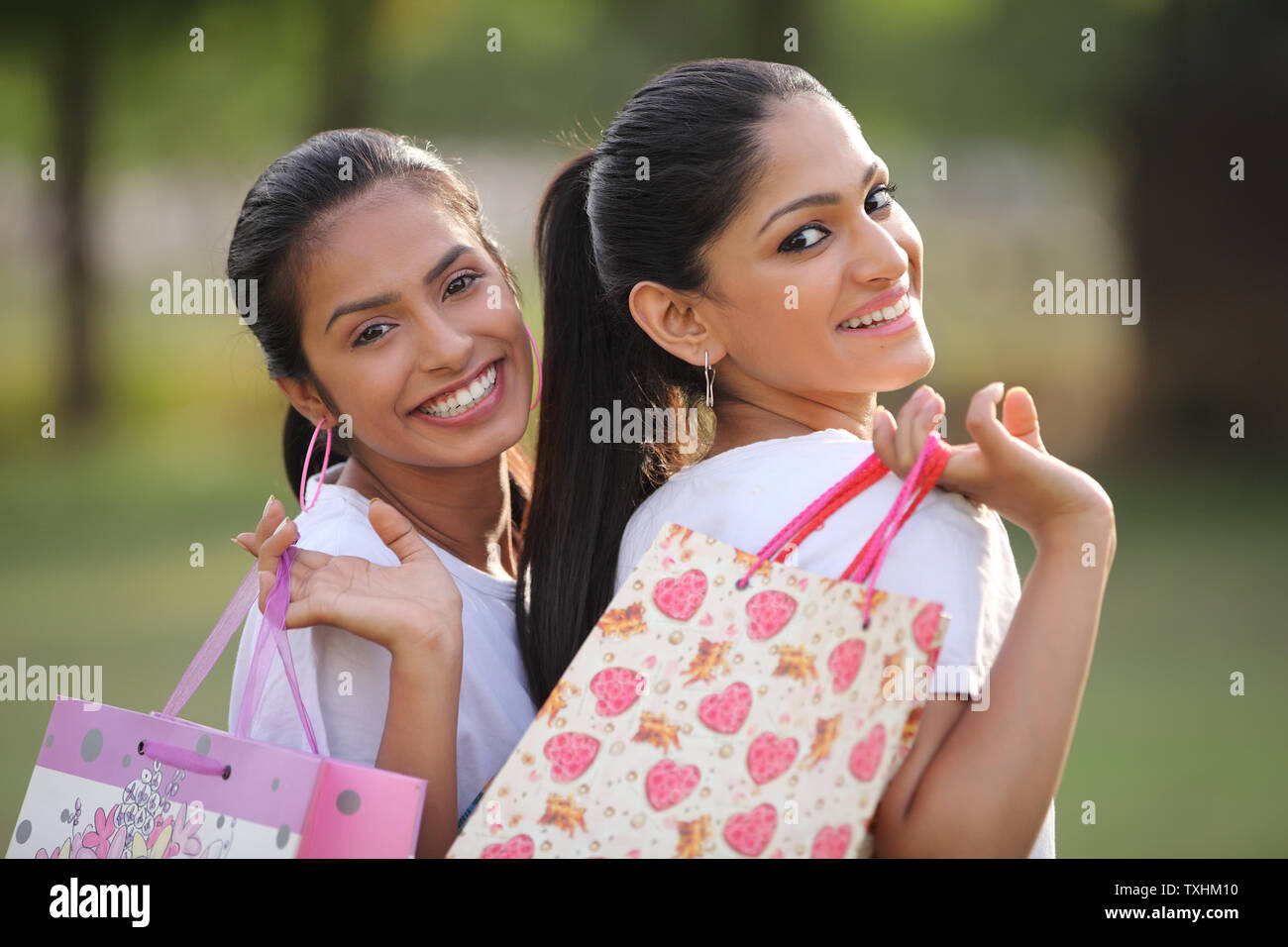 Two friends carrying shopping bags and smiling Stock Photo - Alamy