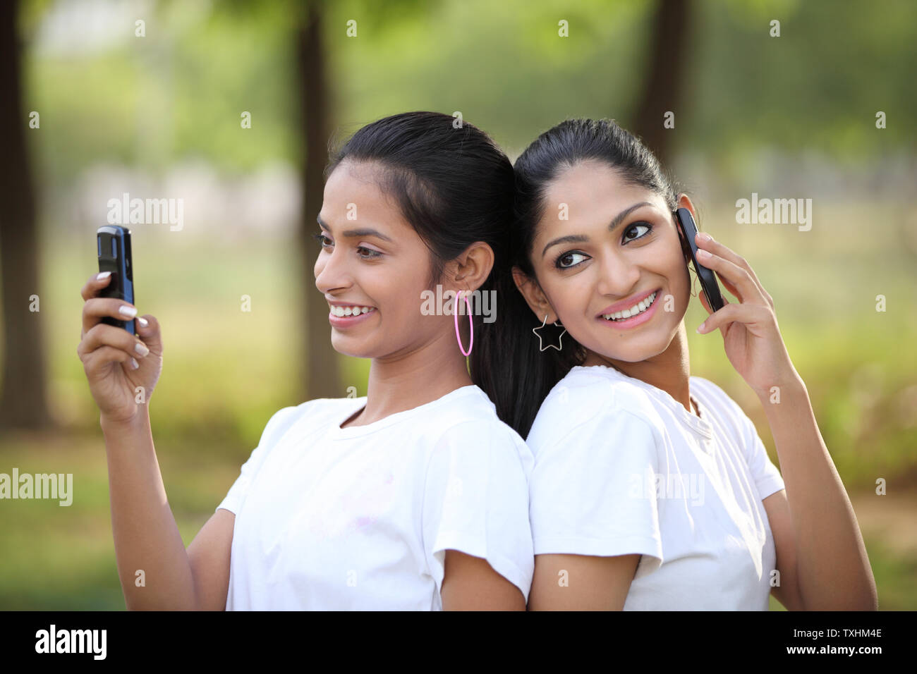 Two friends using mobile phone and smiling Stock Photo - Alamy