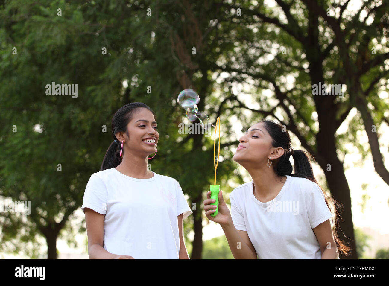Two friends playing with bubbles Stock Photo - Alamy