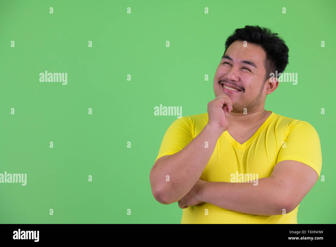 Happy young handsome overweight Asian man thinking Stock Photo - Alamy