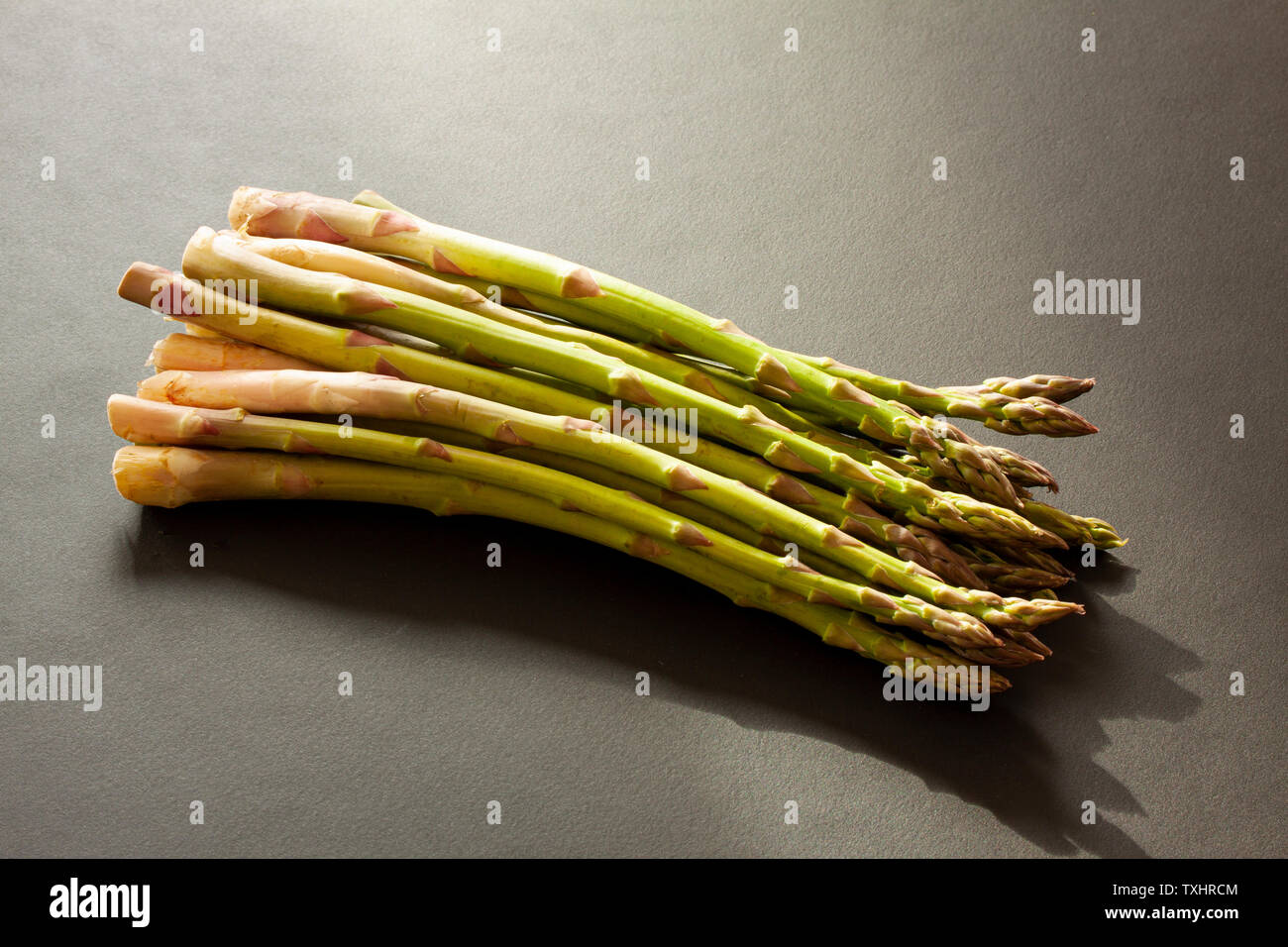 Bundle of green asparagus on black background and light effect. Close ...