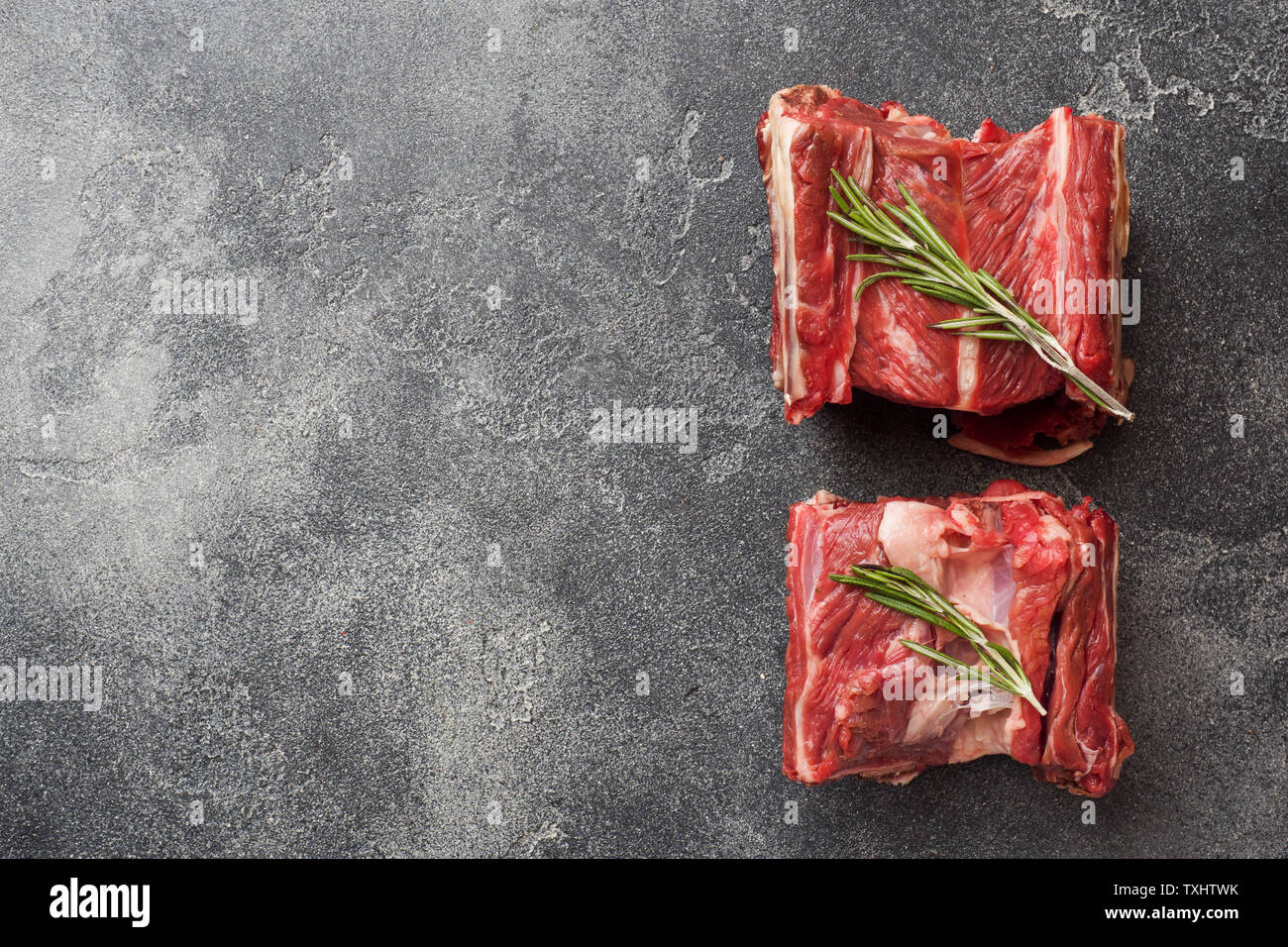 Fresh raw piece of beef rib with meat on a dark concrete background ...