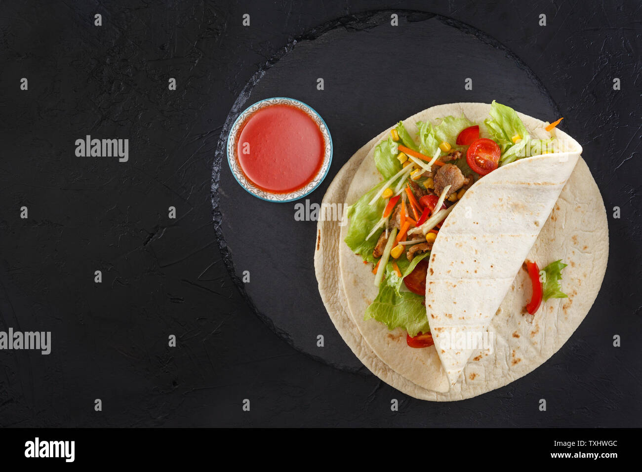 Burritos wraps with chicken and vegetables on black slate. Chicken burrito, mexican food Stock ...