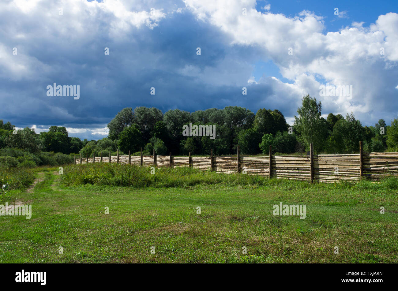 Wooden fence set in a forest area next to a rural road in the ...