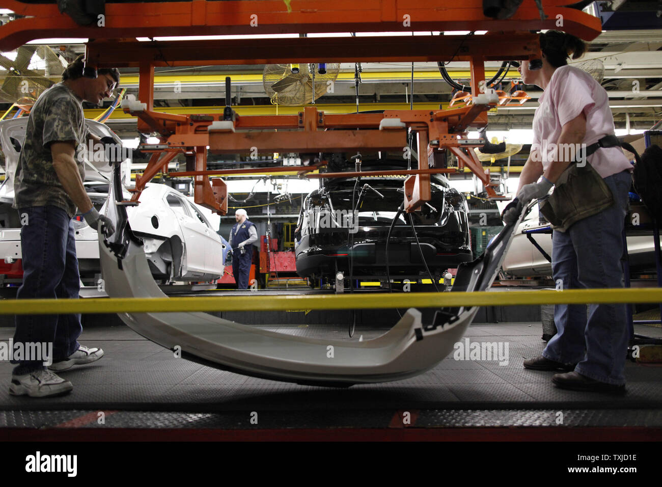 Workers install the bumper cover for a car at the Ford Chicago Assembly ...