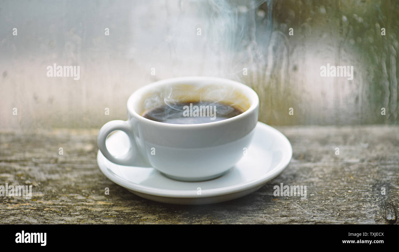 Wet glass window and cup of hot coffee. Autumn cloudy weather better ...