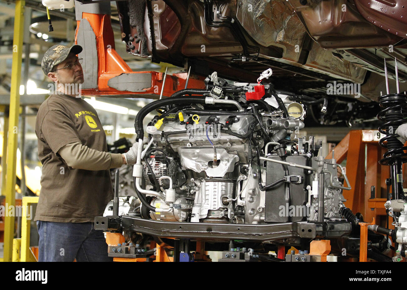 A worker prepares to install an engine into a Ford Explorer Ford's ...