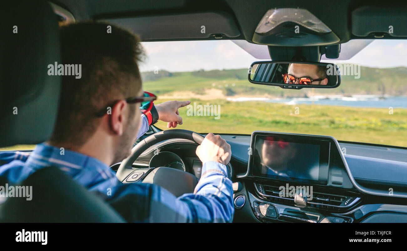 Young man holding steering and pointing driving Stock Photo - Alamy