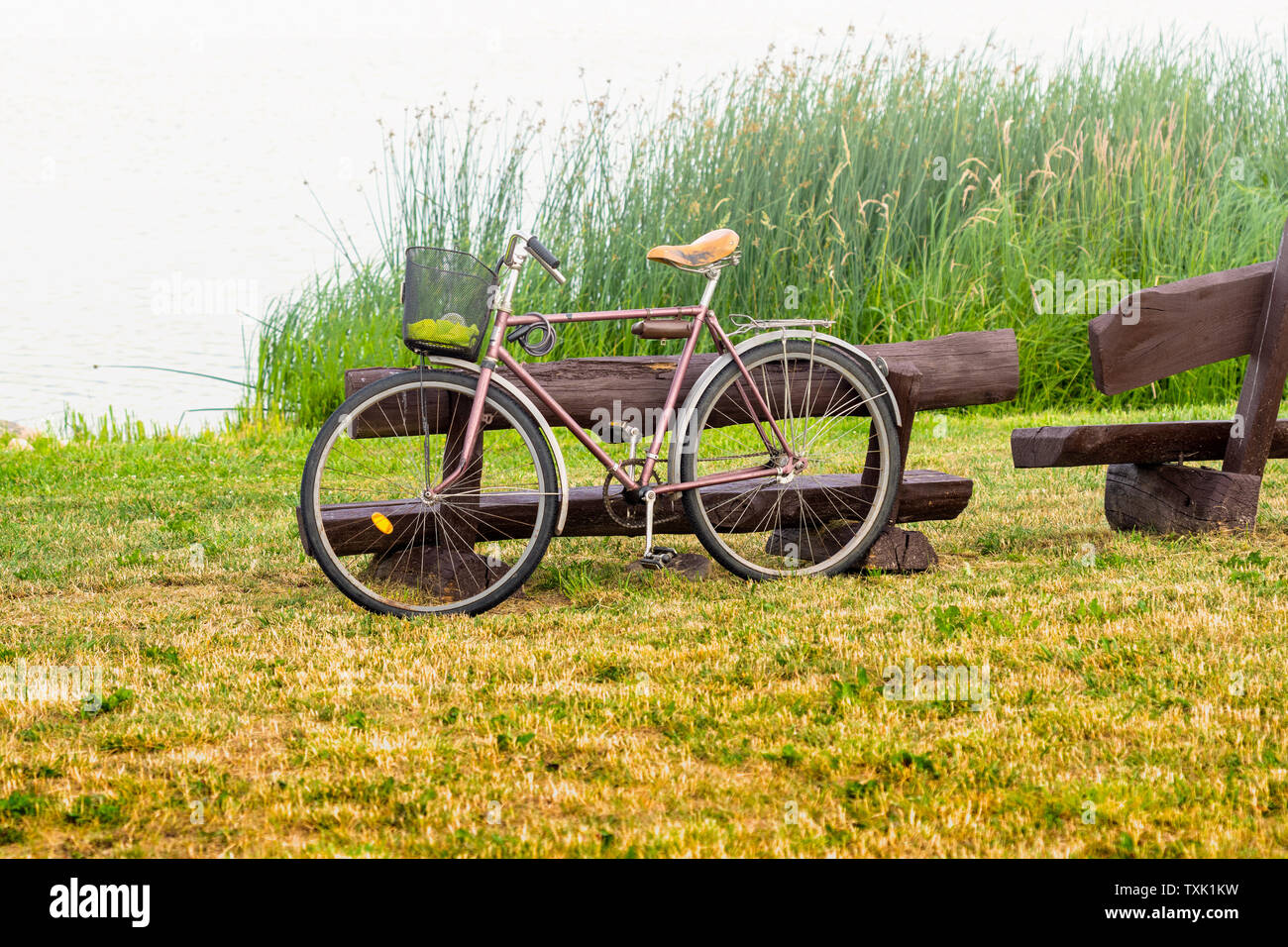 Old bicycle leaning against wooden bench on the lake side Stock Photo ...