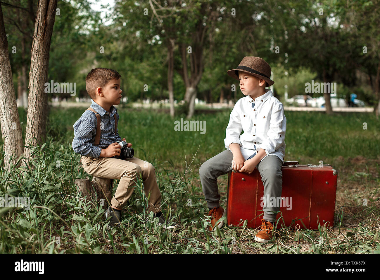 two Caucasian boy brothers in vintage clothes sit opposite each other ...