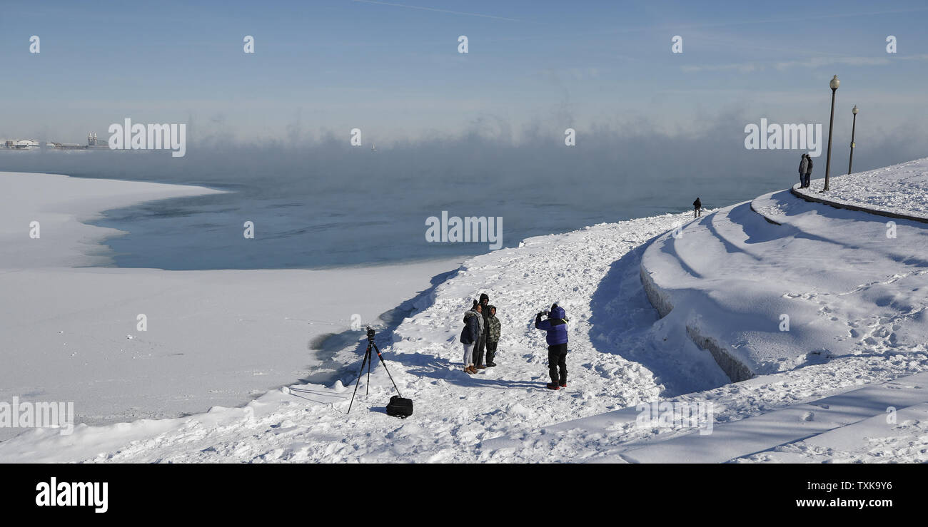 People take pictures as steam rises from the Lake Michigan in Chicago ...