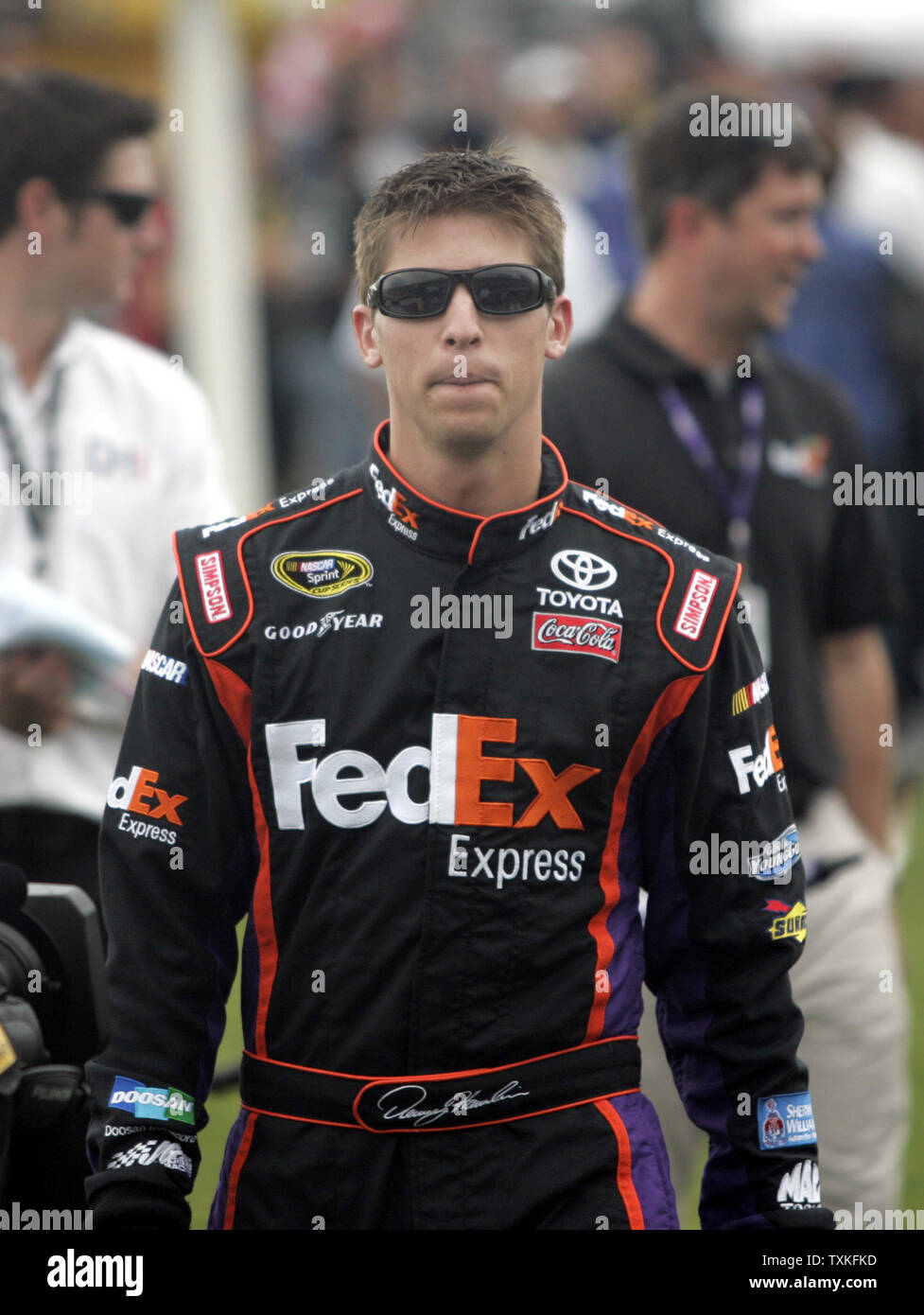 Race car driver Denny Hamlin walks down pit road before the NASCAR Coca ...
