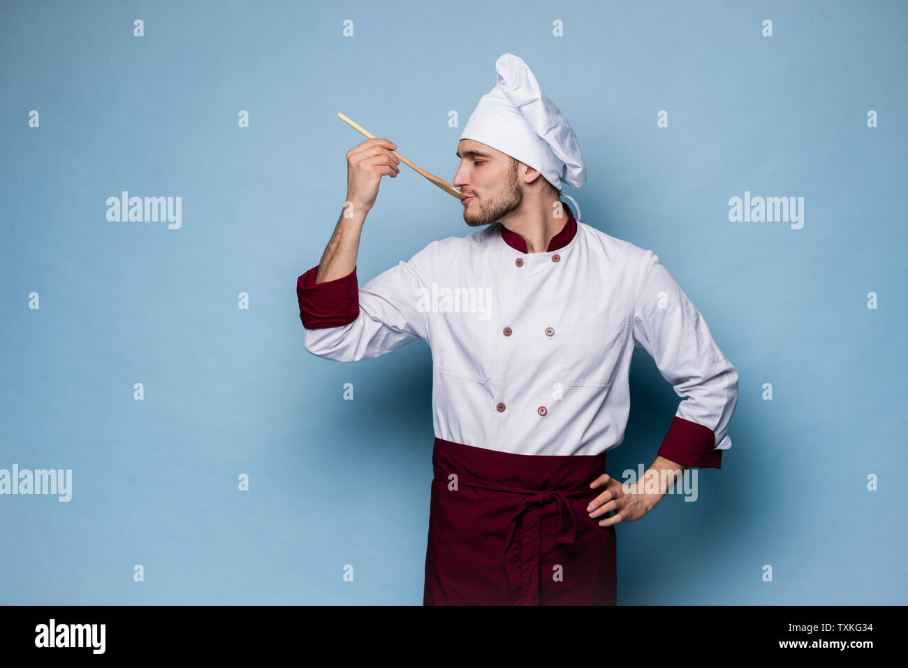 Chef trying meal. Positive professional chef in white uniform trying ...