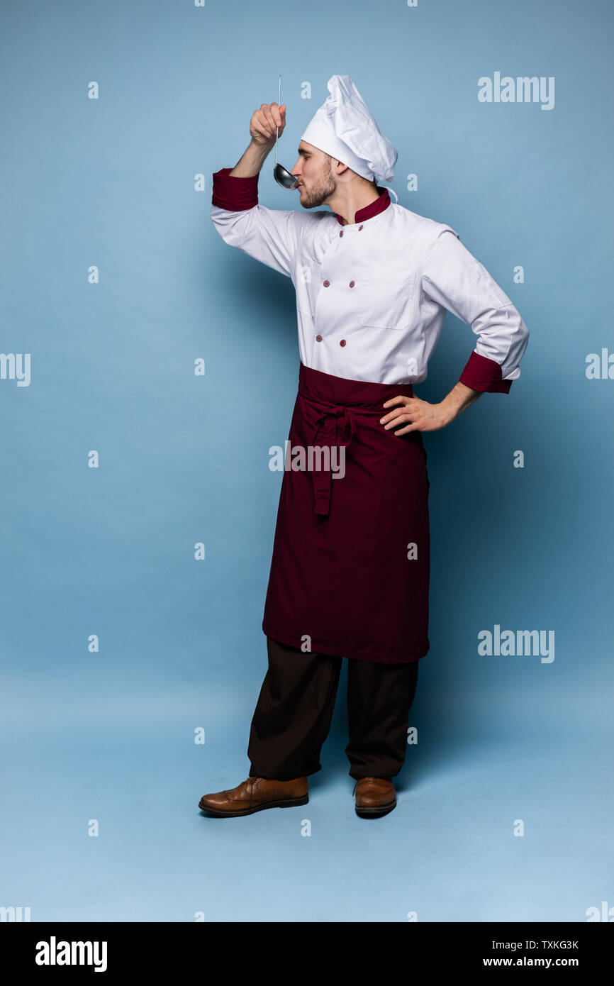 Chef trying meal. Positive professional chef in white uniform trying ...