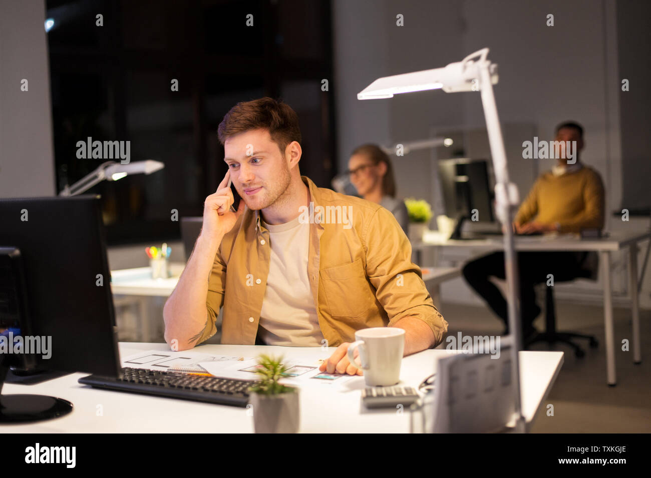 man calling on smartphone at night office Stock Photo - Alamy