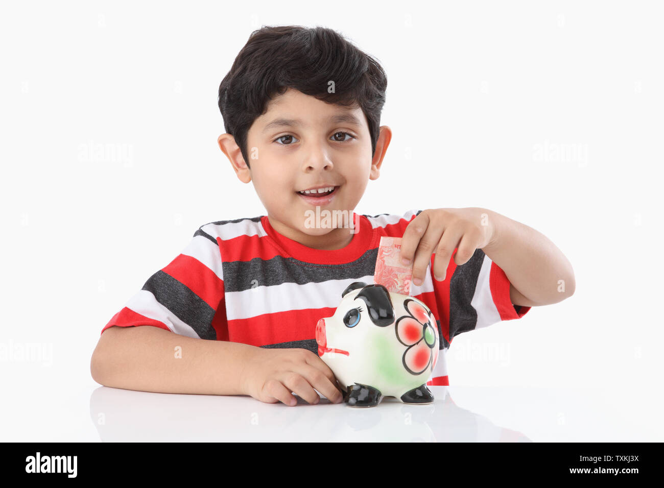 Boy putting banknote into a piggy bank Stock Photo - Alamy