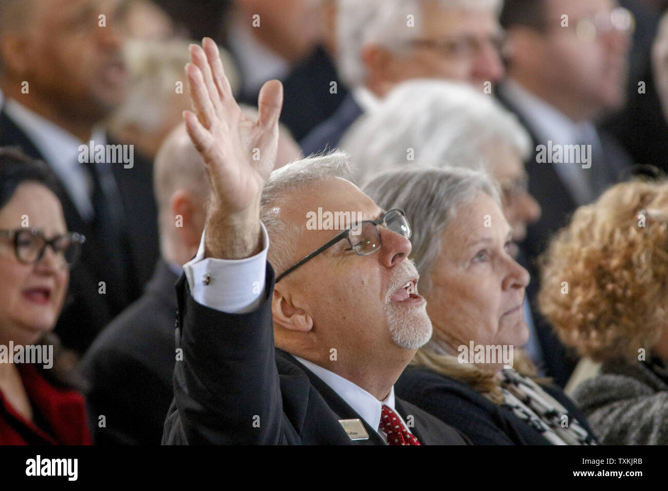 A guest raises his hand in praise during a hymn at the private funeral ...