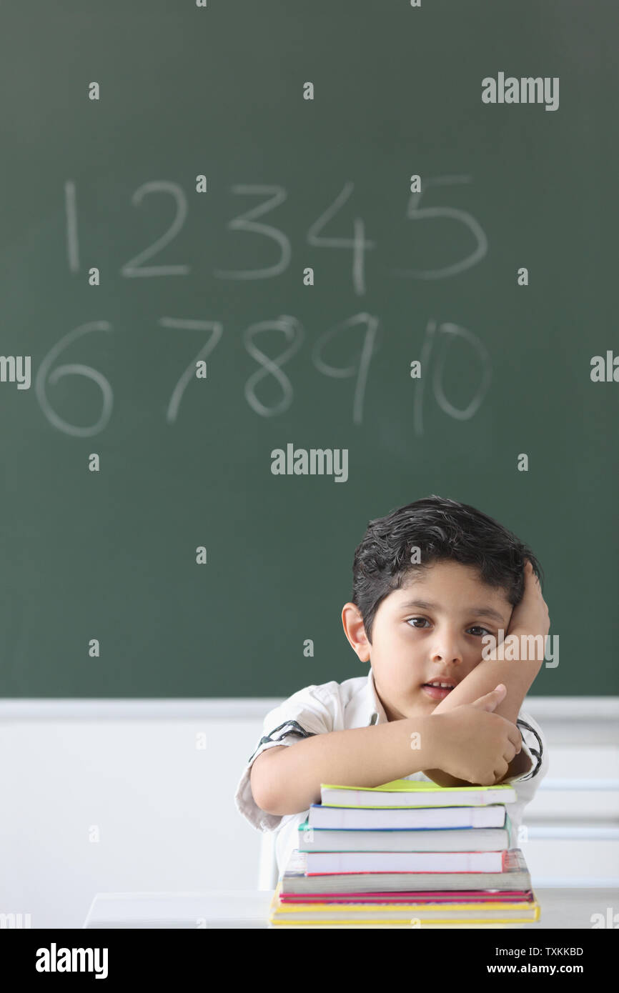 Schoolboy leaning on books in a classroom Stock Photo - Alamy