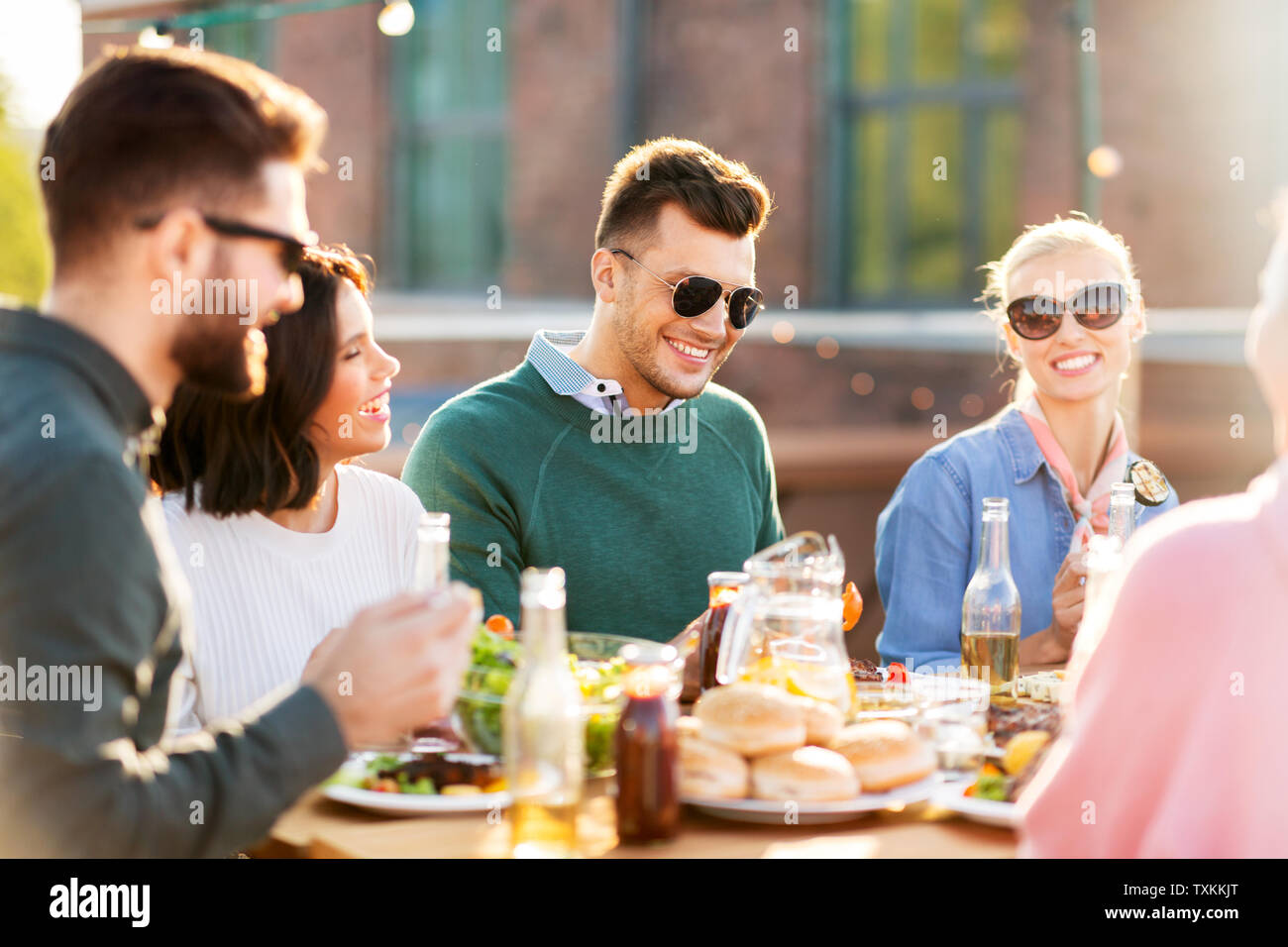 happy friends eating and drinking at rooftop party Stock Photo - Alamy