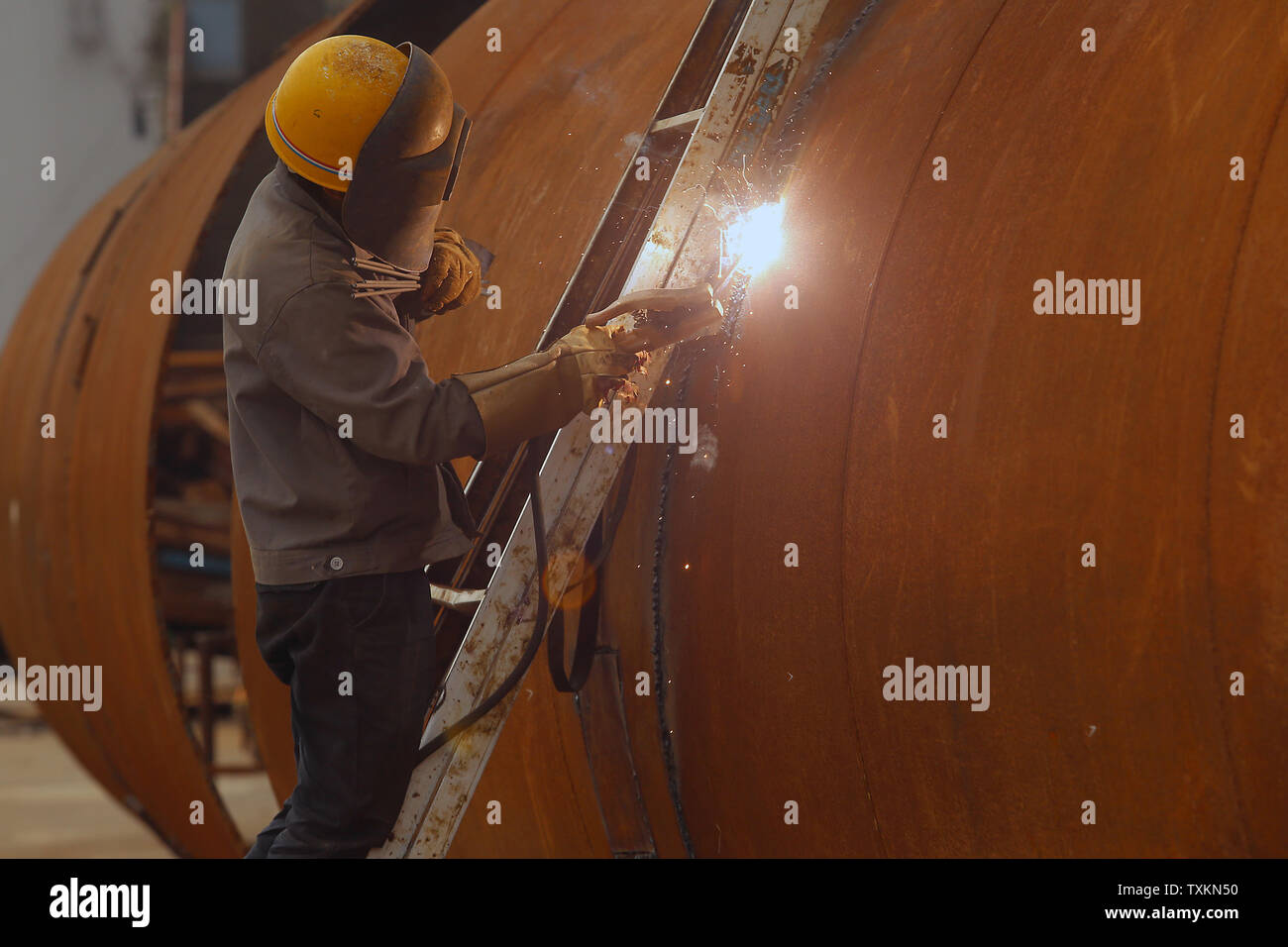 A Chinese welder connects segments of a huge steel pipe in Chongqing ...