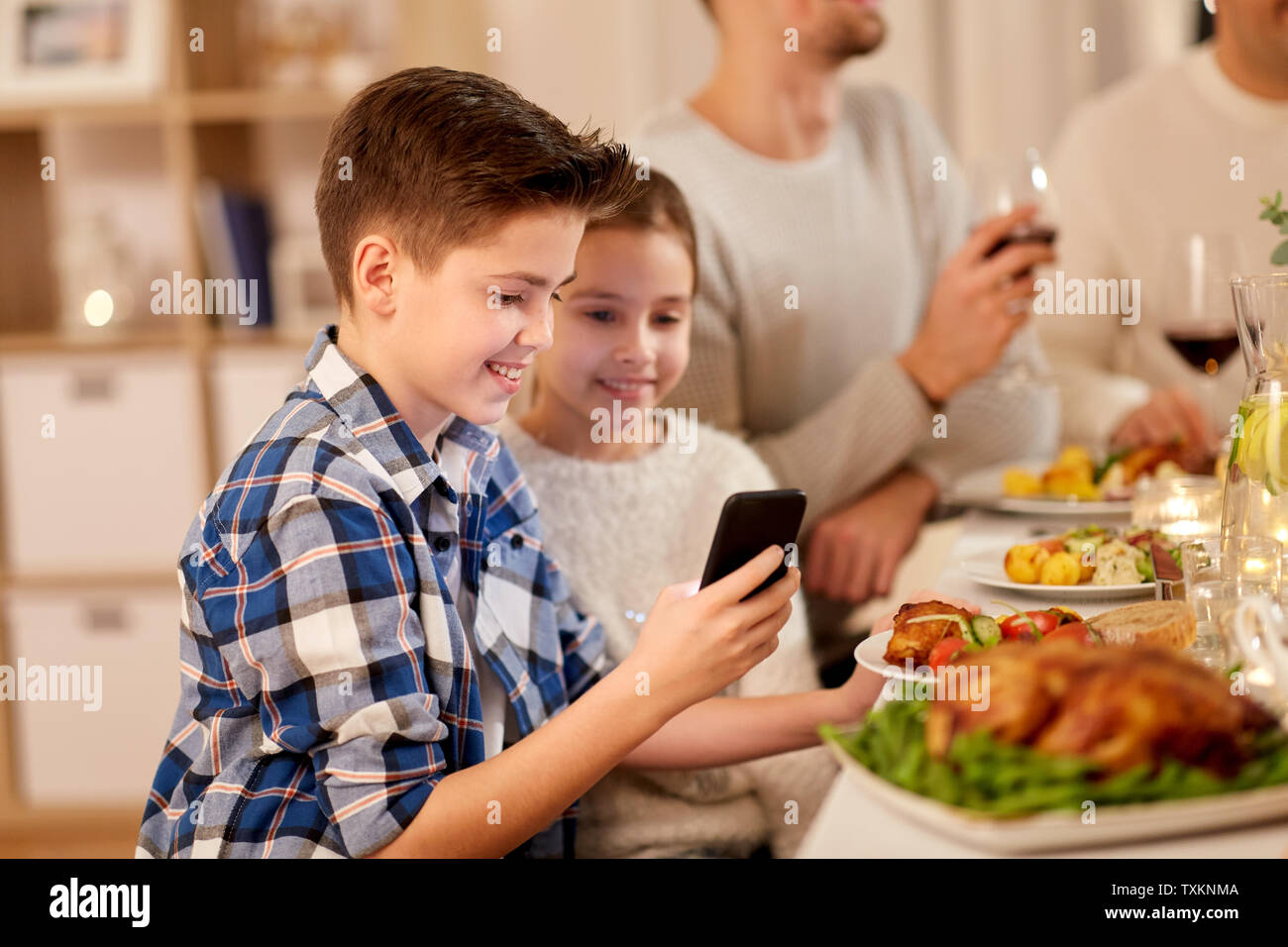 boy with sister using smartphone at family dinner Stock Photo - Alamy