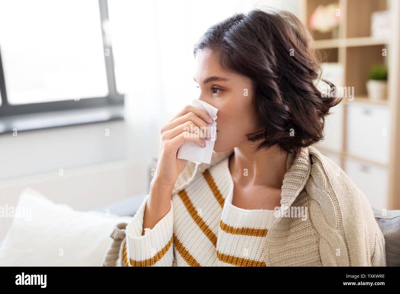 sick woman blowing nose in paper tissue at home Stock Photo - Alamy