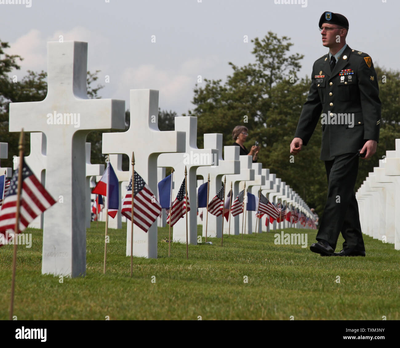 A soldier walks past rows of white crosses at the Normandy American ...