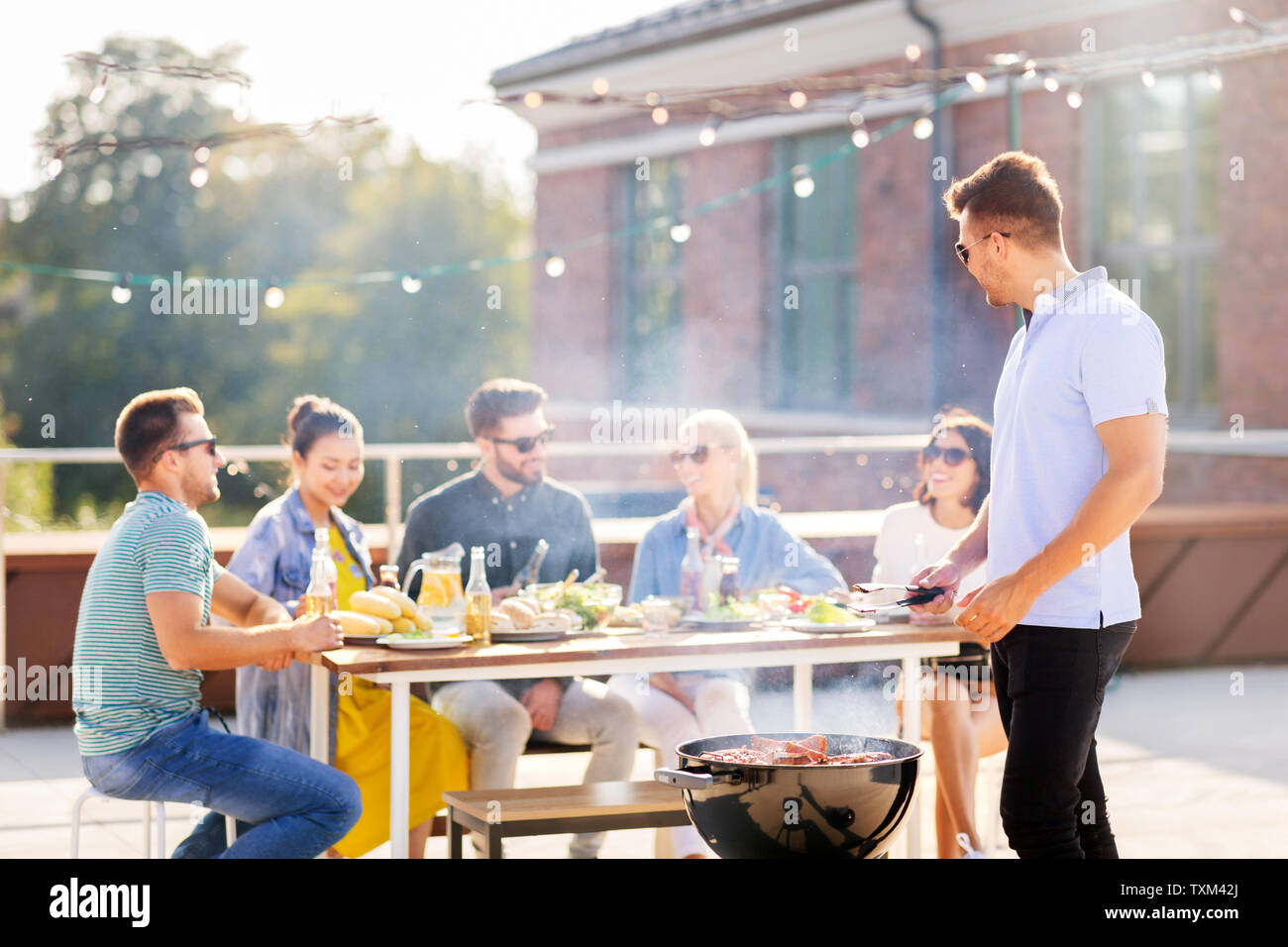 man grilling meat on bbq at rooftop party Stock Photo - Alamy