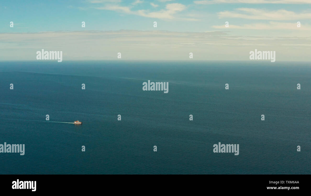 Small passenger ferry cruising in the open blue sea against blue sky ...