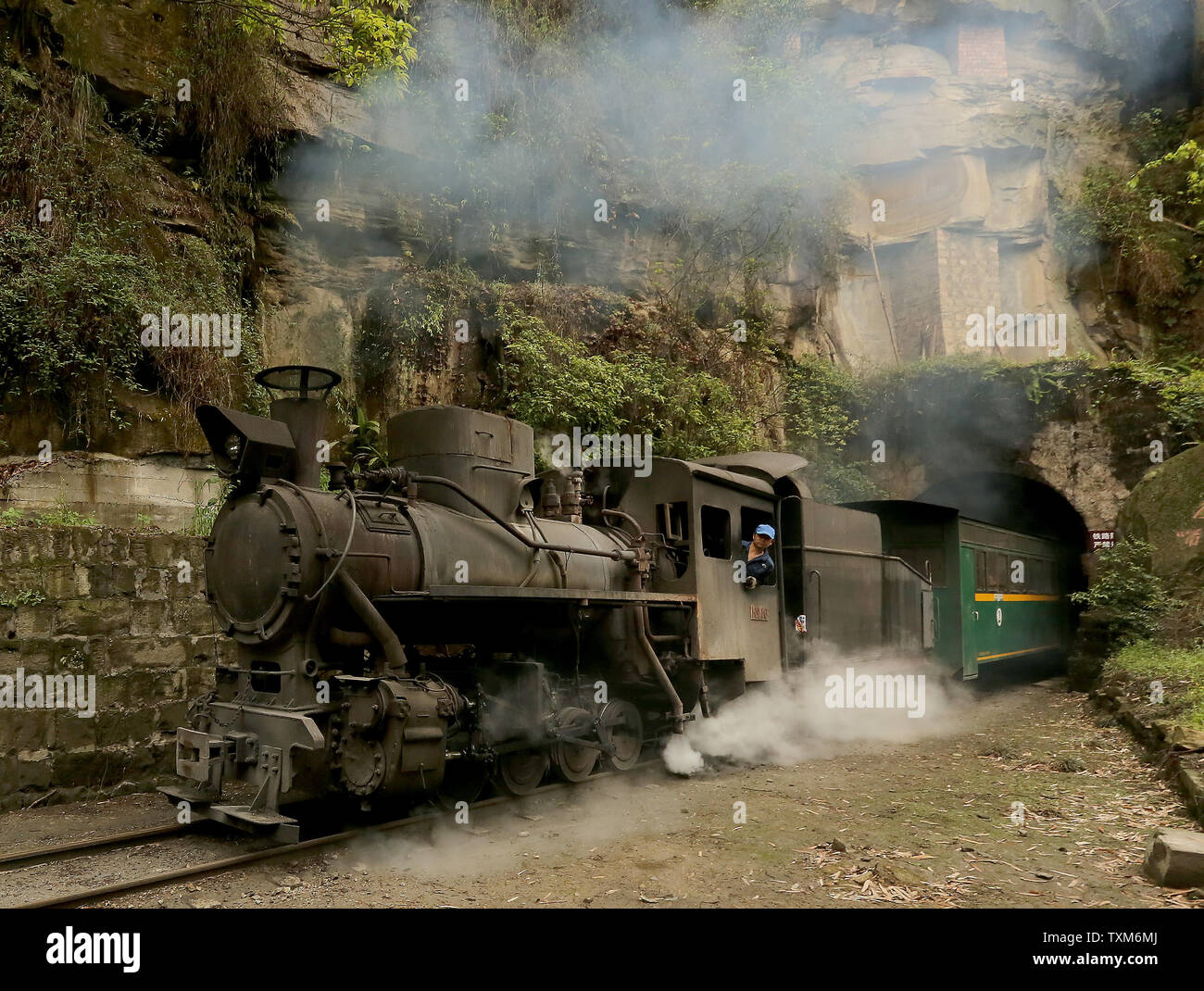 A passenger steam train passes through a tunnel near Jiayang, a small ...