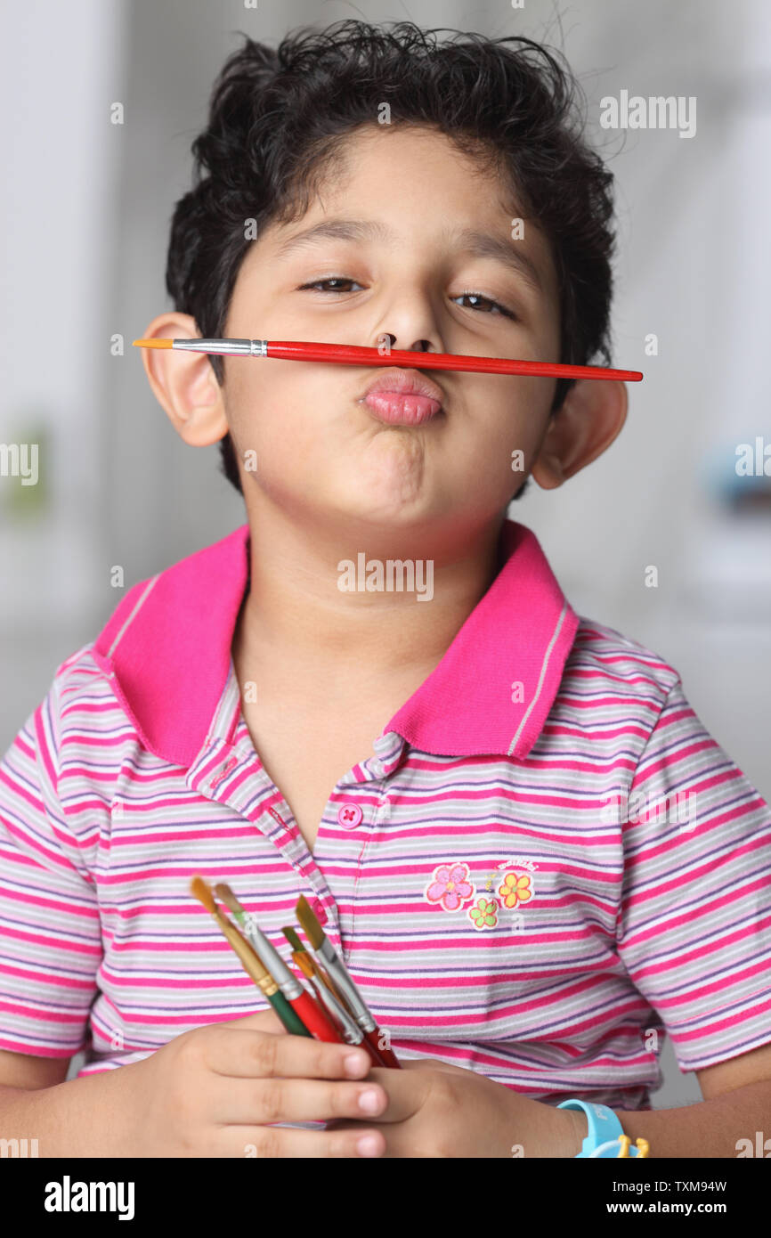Boy balancing a paintbrush between nose and lips Stock Photo - Alamy