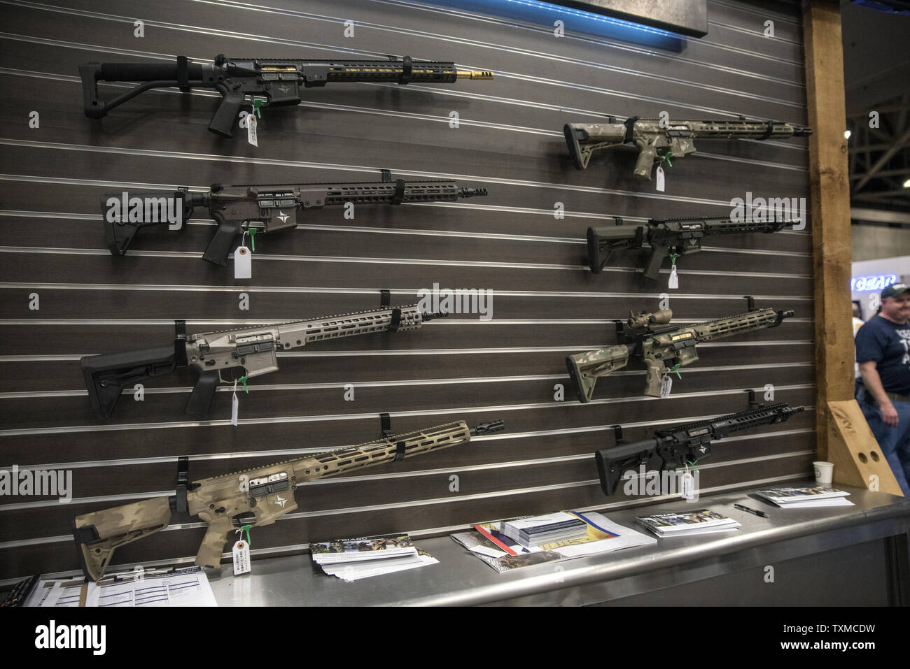 Guns hang in display at a booth on the floor of the exhibition hall at ...
