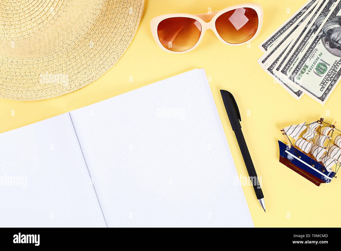 Blank notepad on a yellow background, sun glasses, hat, money. Top view ...