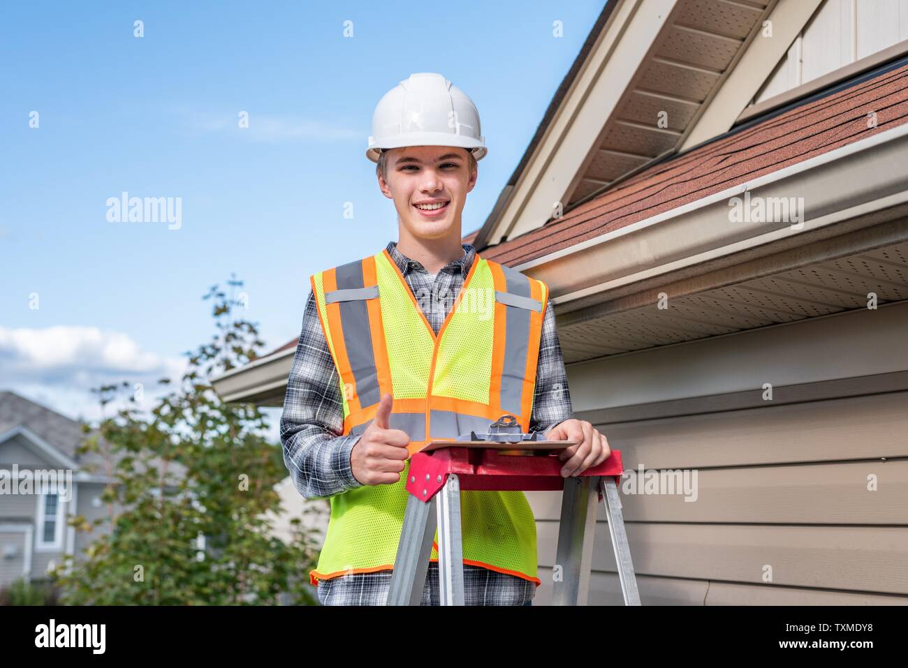 Home inspector standing on a ladder and providing an inspection to the ...