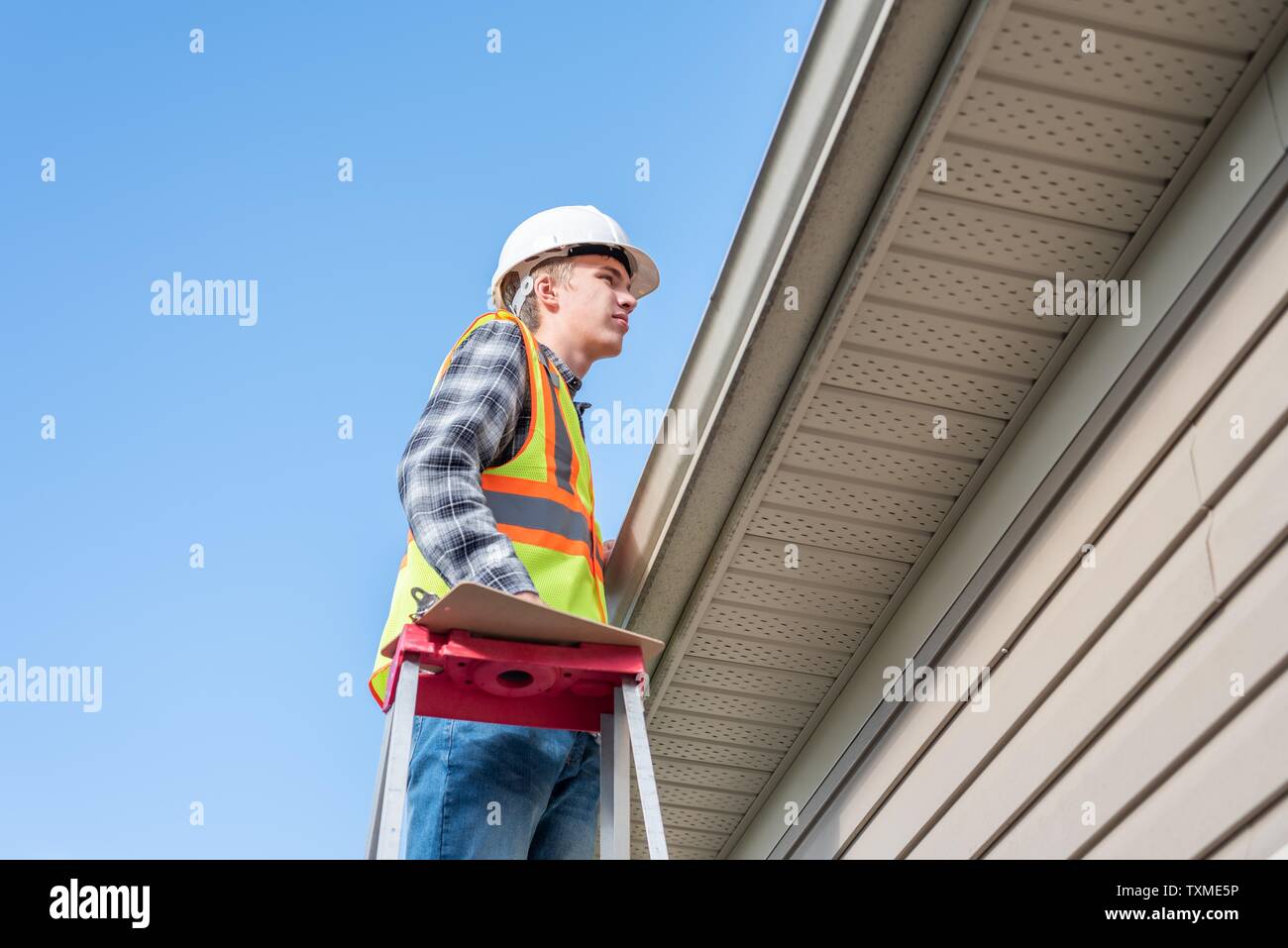 Home inspector standing on a ladder and providing an inspection to the ...