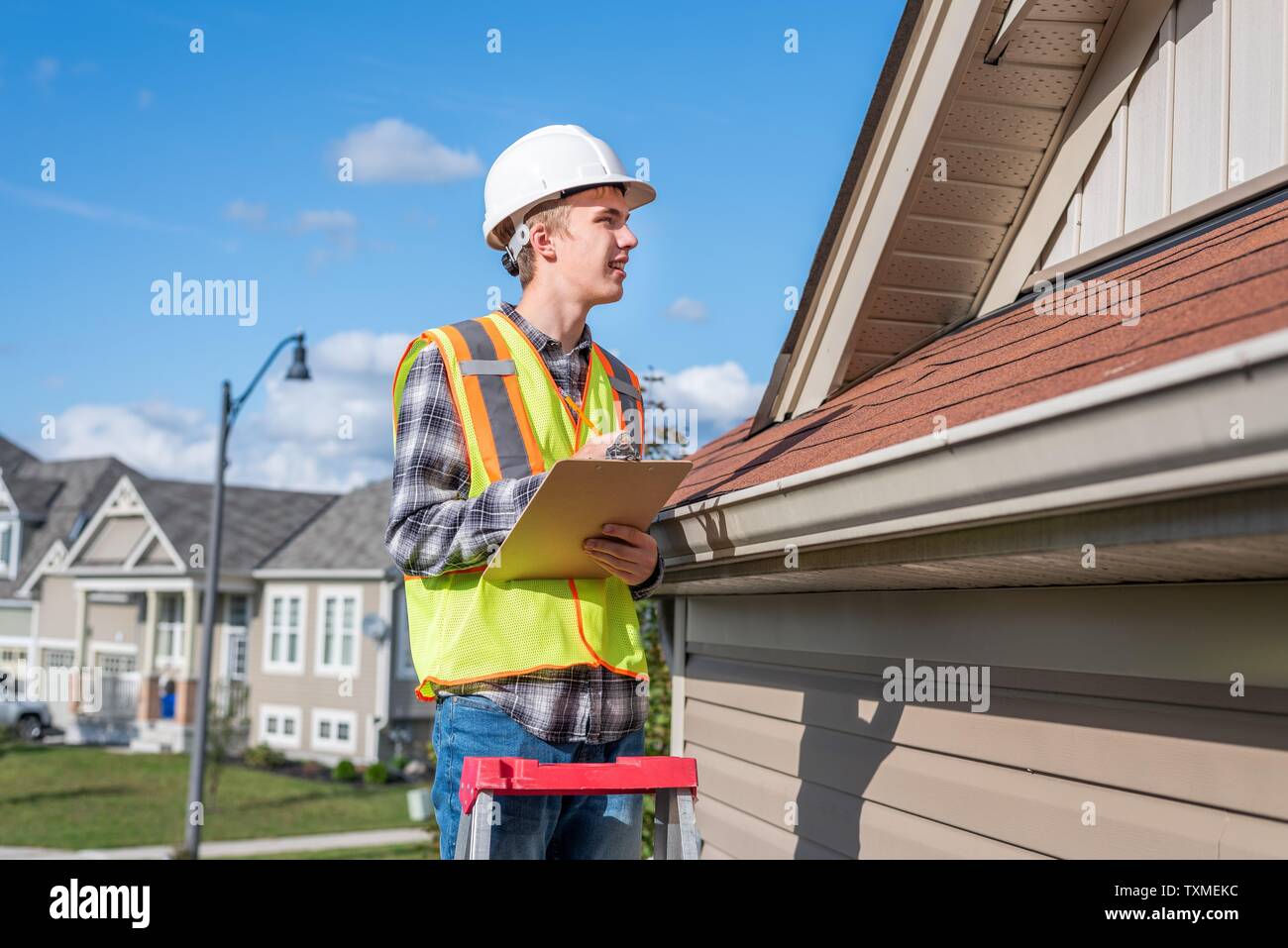 Home inspector standing on a ladder and providing an inspection to the ...