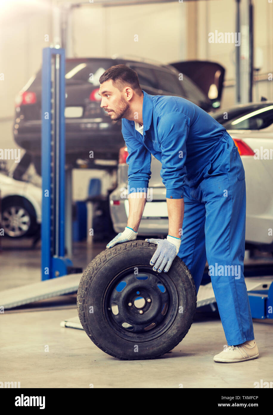 mechanic with wheel tire at car workshop Stock Photo - Alamy