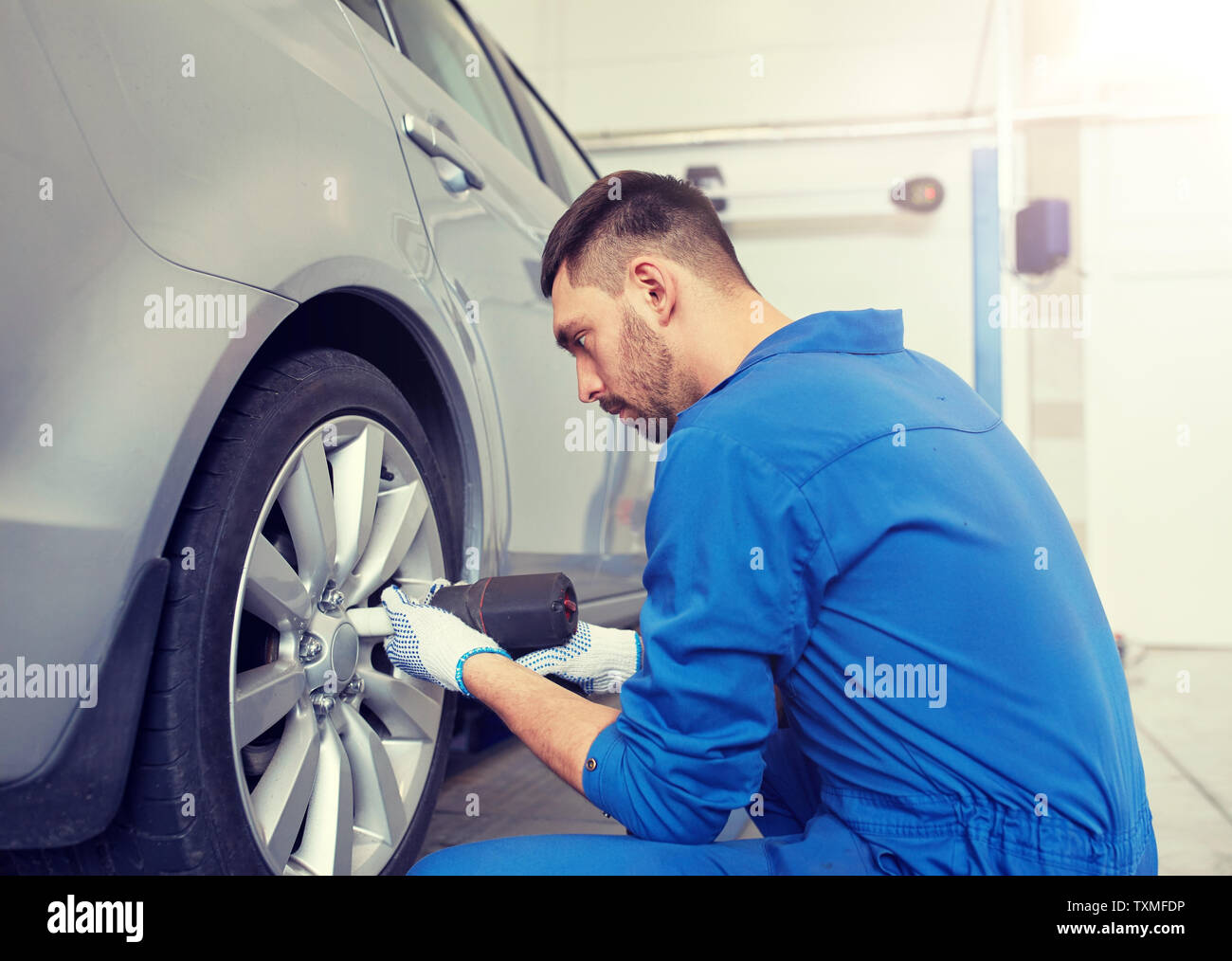 mechanic with screwdriver changing car tire Stock Photo - Alamy