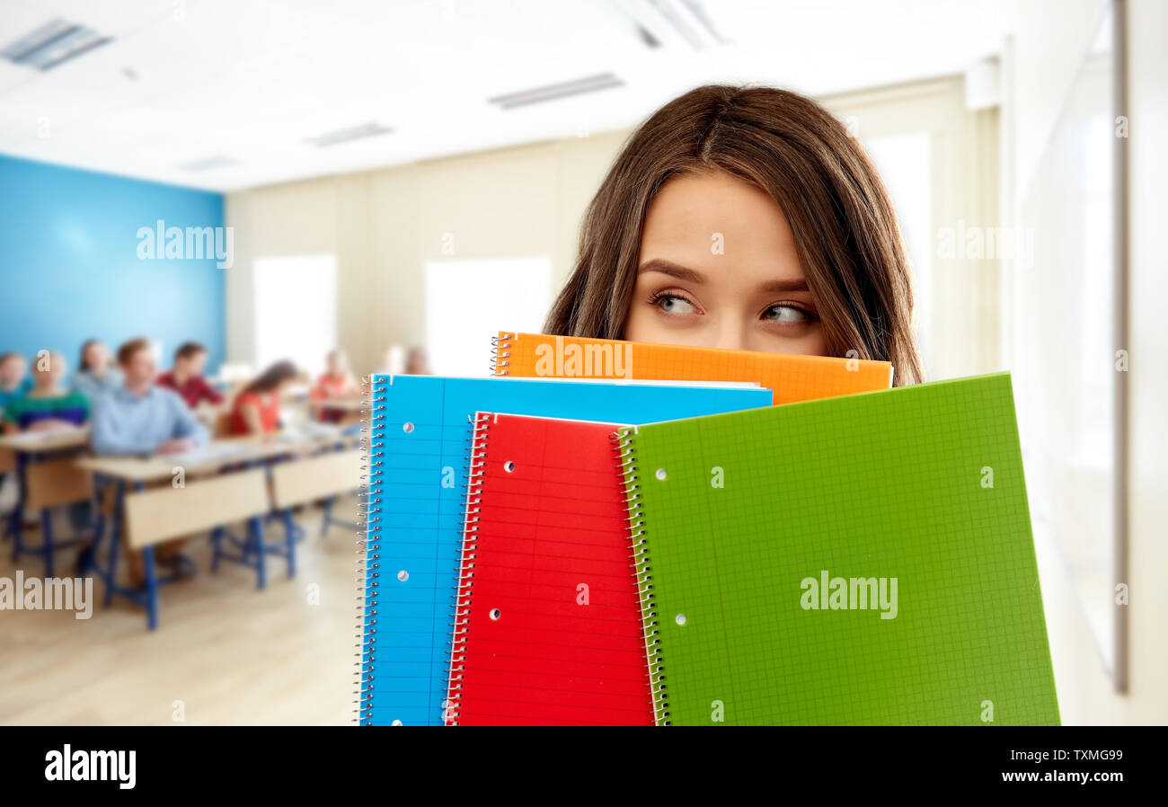 student girl hiding behind notebooks at school Stock Photo - Alamy